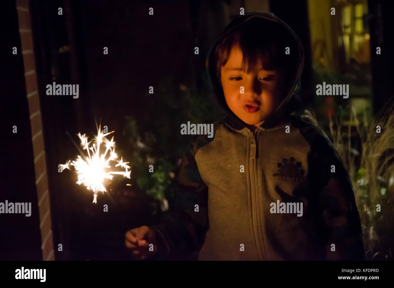 A young boy playing with a sparkler in the back garden Stock Photo - Alamy