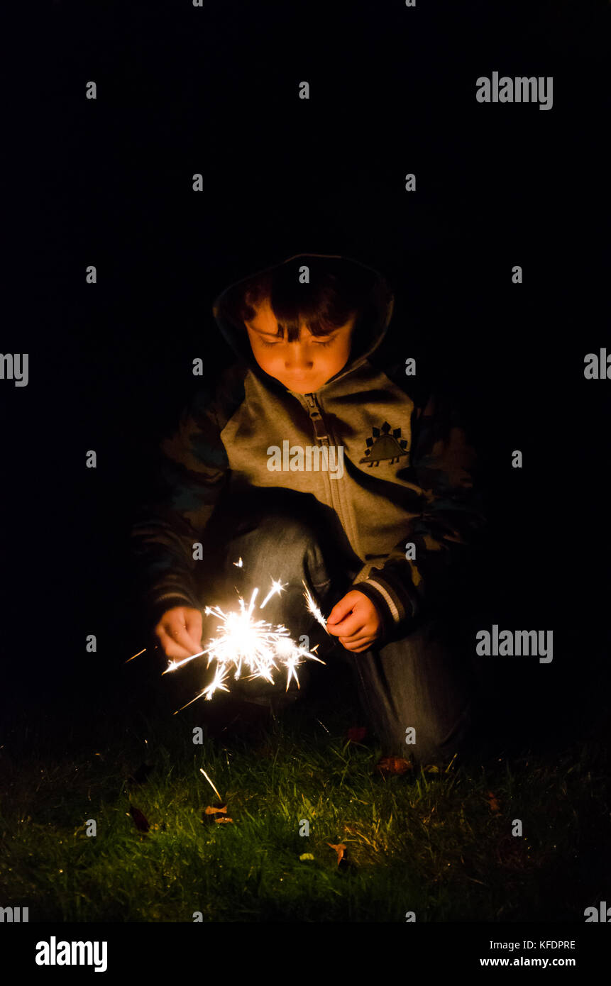 A young boy playing with a sparkler in the back garden Stock Photo - Alamy