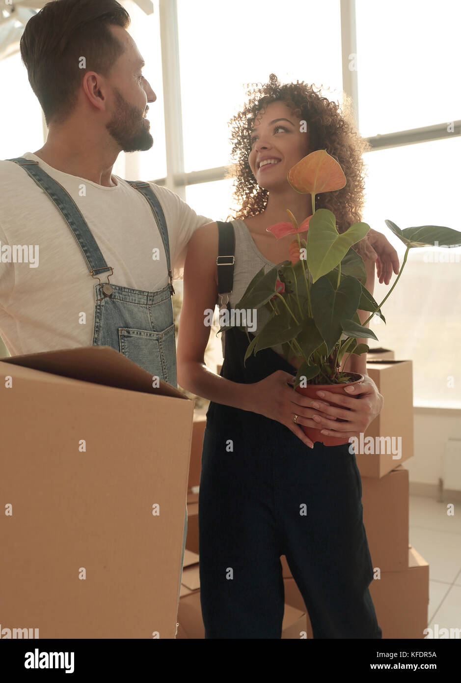 beautiful young couple is carrying things into a new home. Photo has a ...