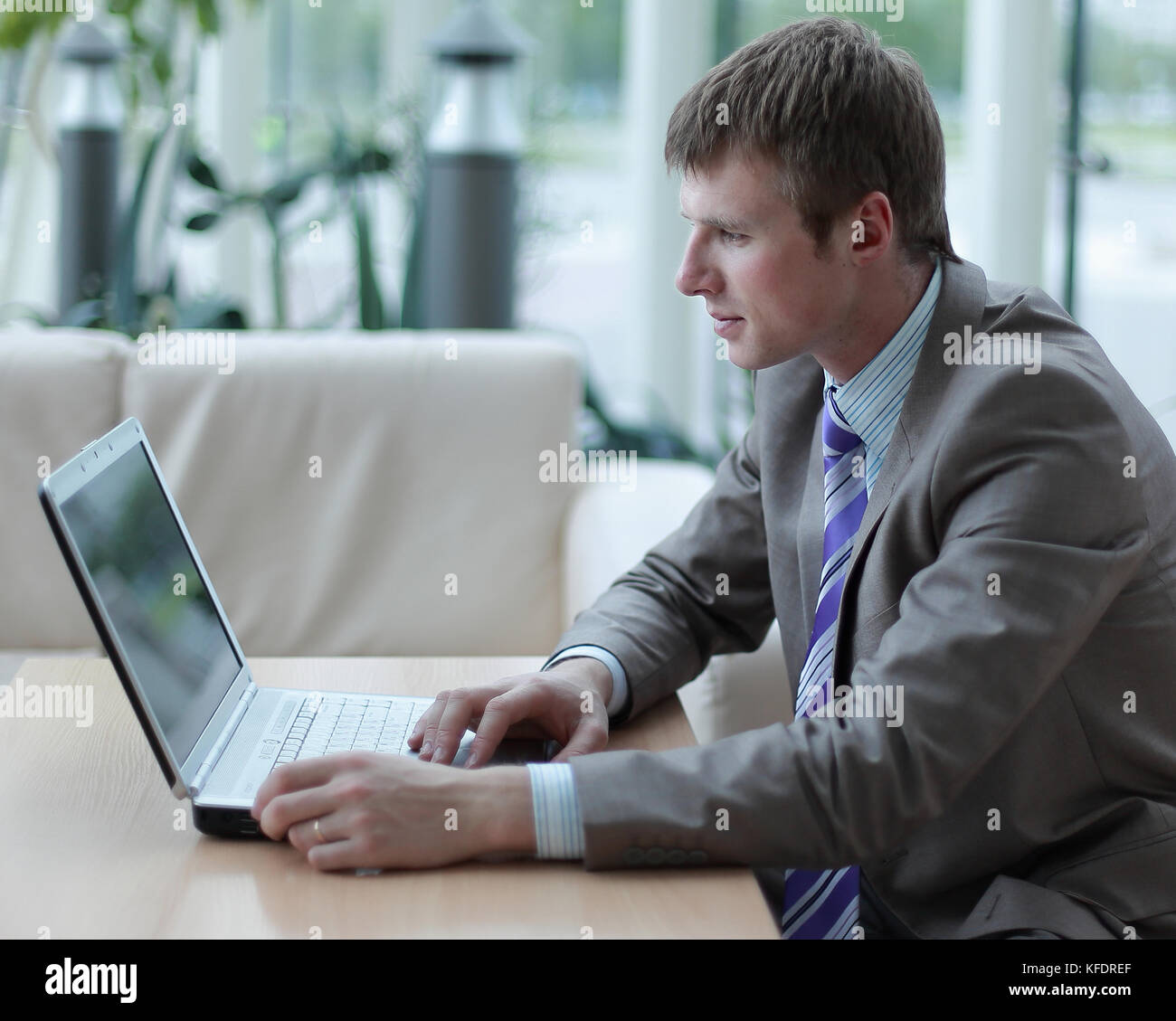 Portrait of young man sitting at his desk in the office Stock Photo - Alamy