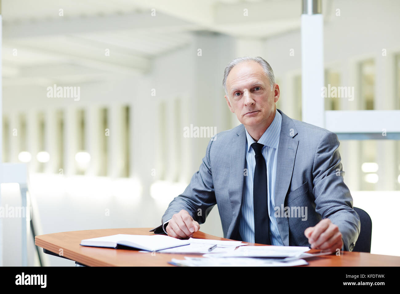 Senior boss in formalwear sitting by workplace in office Stock Photo ...