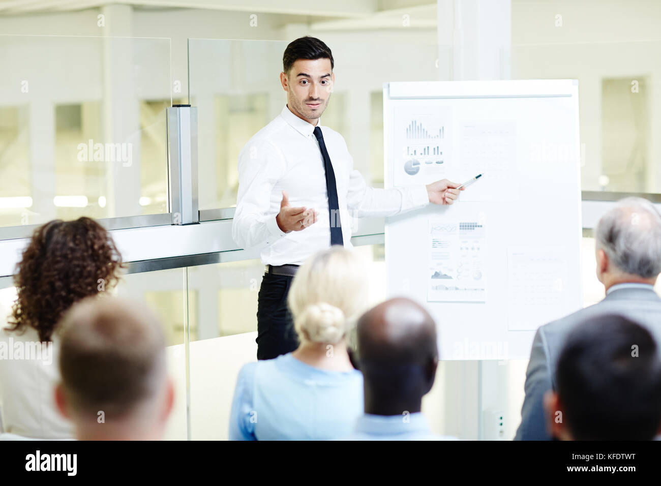 Young coach pointing at data on whiteboard during presentation of his ...