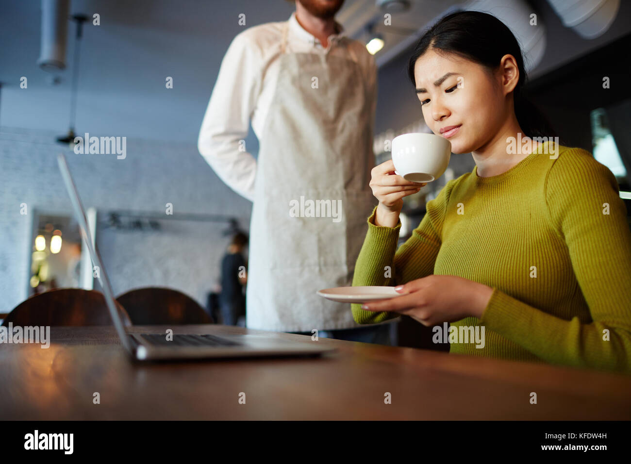 Displeased female with cup of drink smelling it and expressing dislike ...