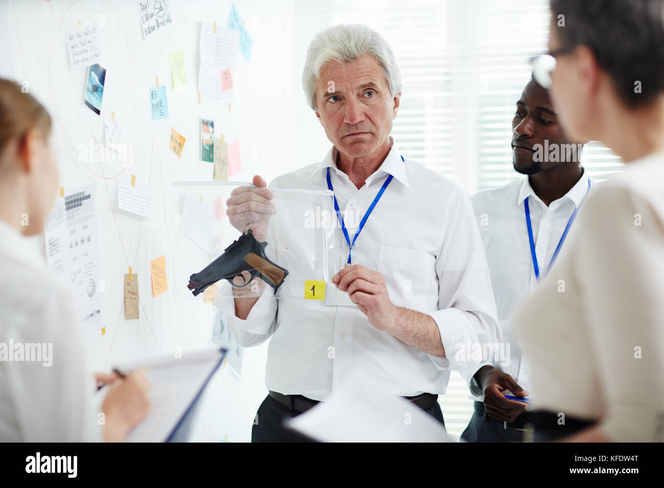 Mature forensic examiner showing gun taken from crime scene to his ...