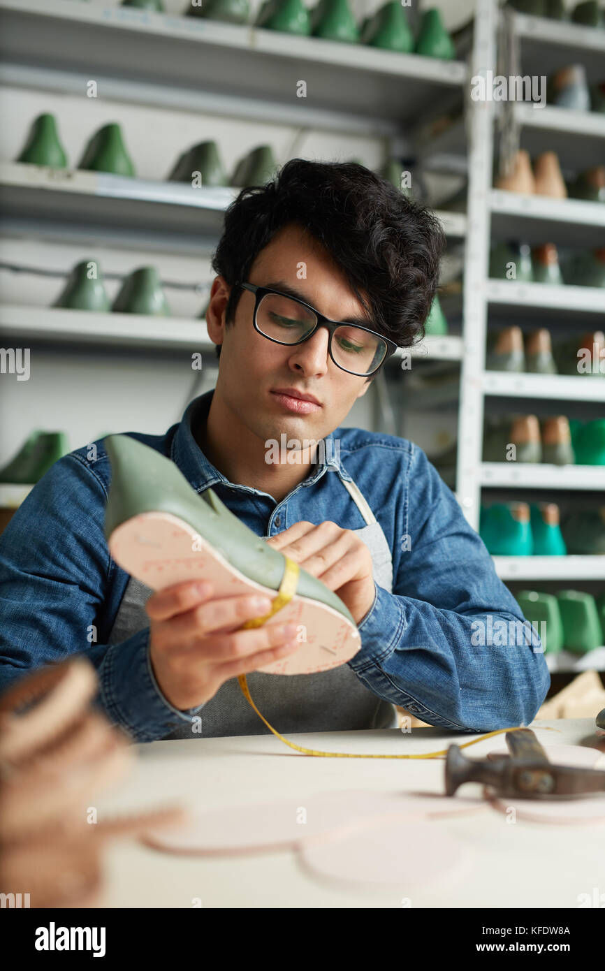 Young shoe designer measuring form of boot in process of work Stock ...