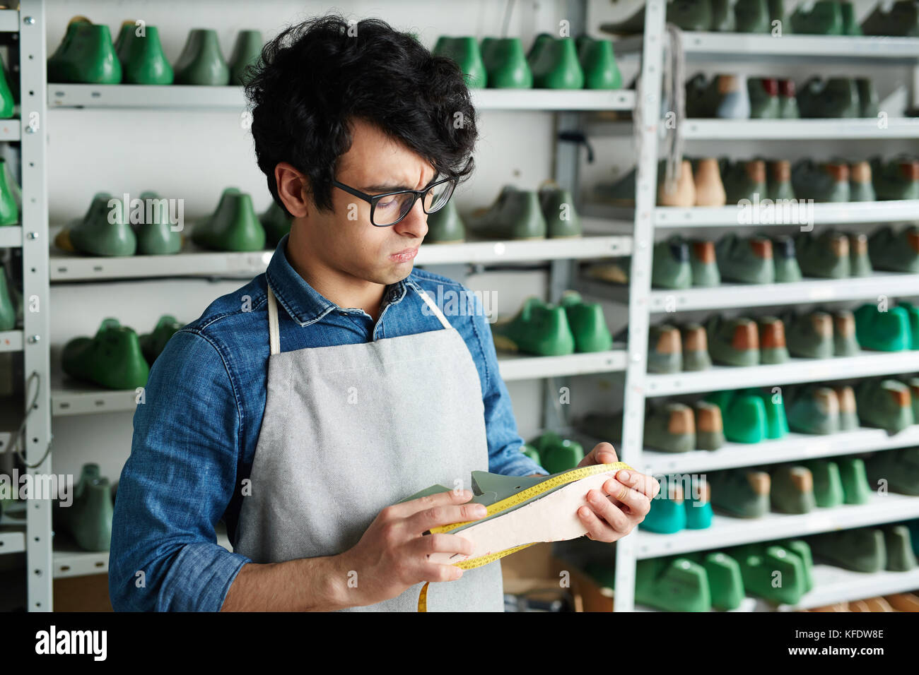 Young shoemaker taking measures of shoe model in his workshop Stock ...