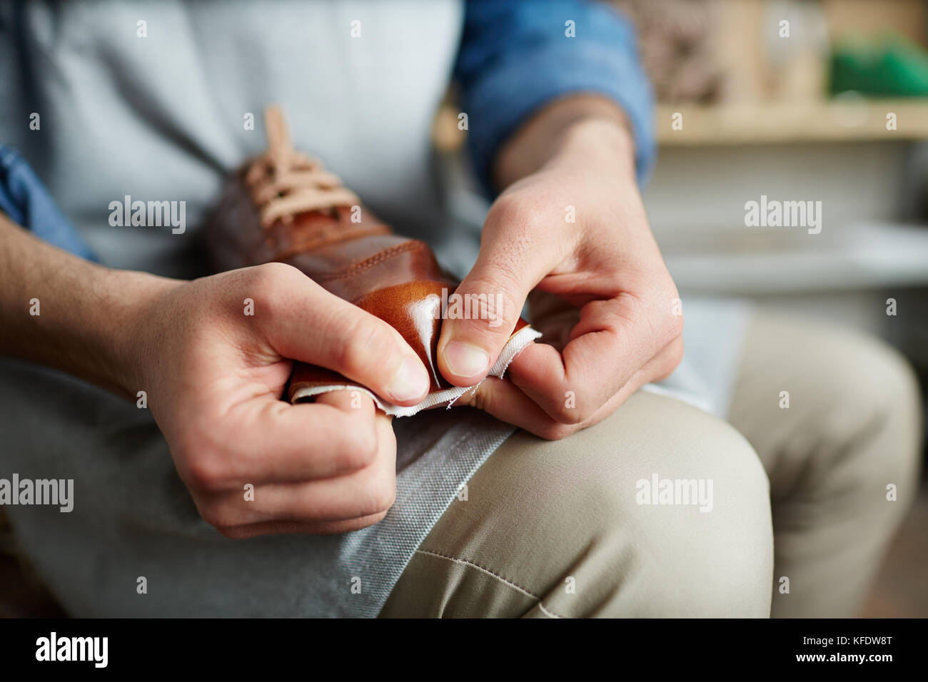 Hands of cobbler stretching brown leather on boot model in workshop ...
