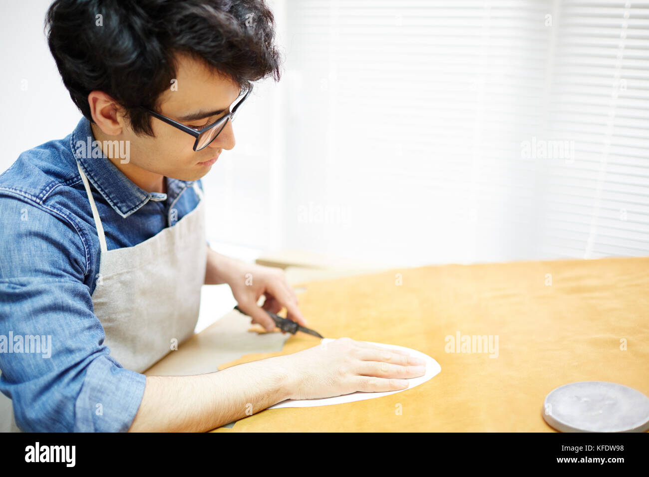 Busy craftsman cutting piece of fabric around paper form while ...