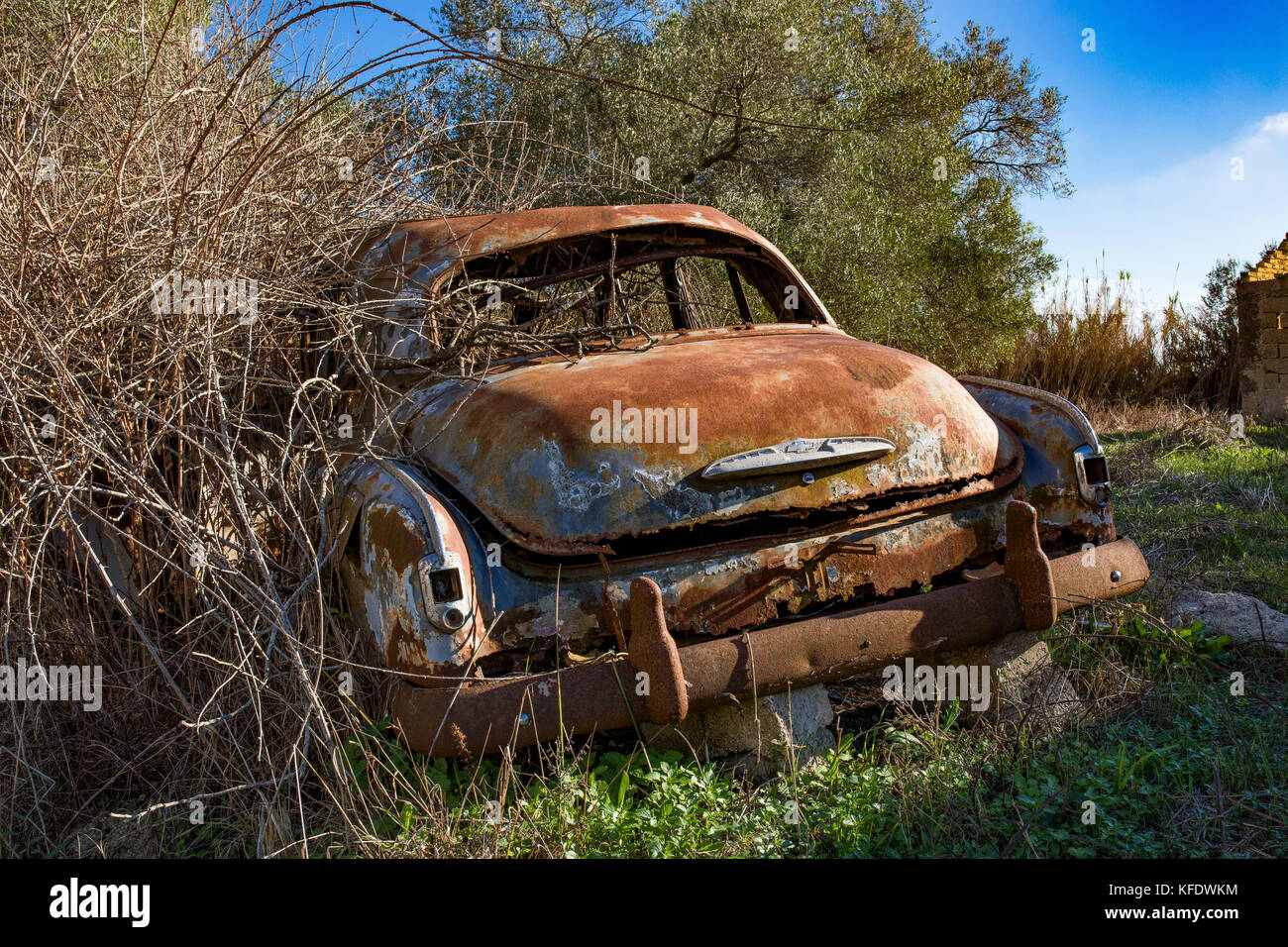 An old or vintage, rusty car wreck in the bush by the road. Ionian ...