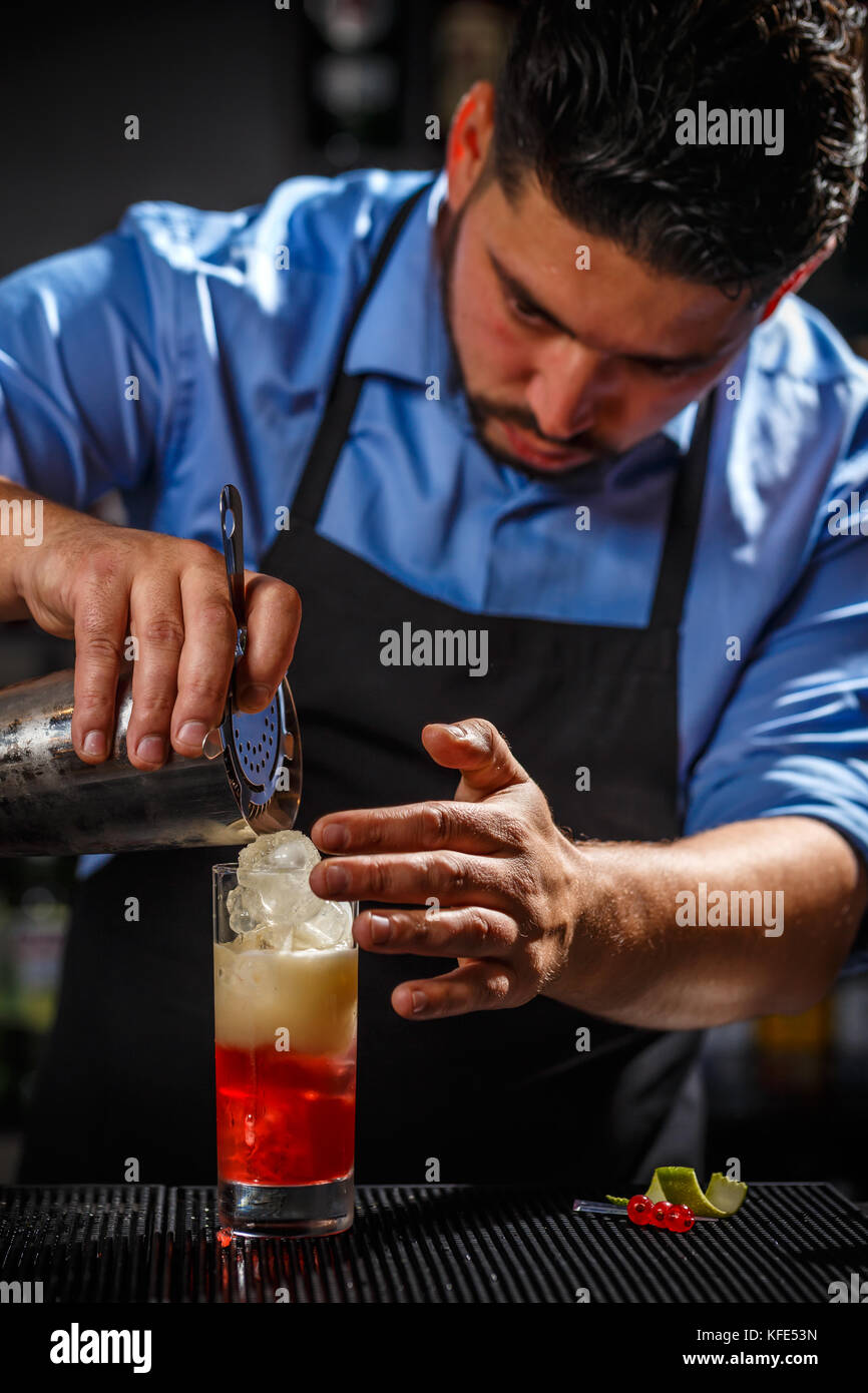 Barman with shaker preparing cocktail at bar Stock Photo - Alamy