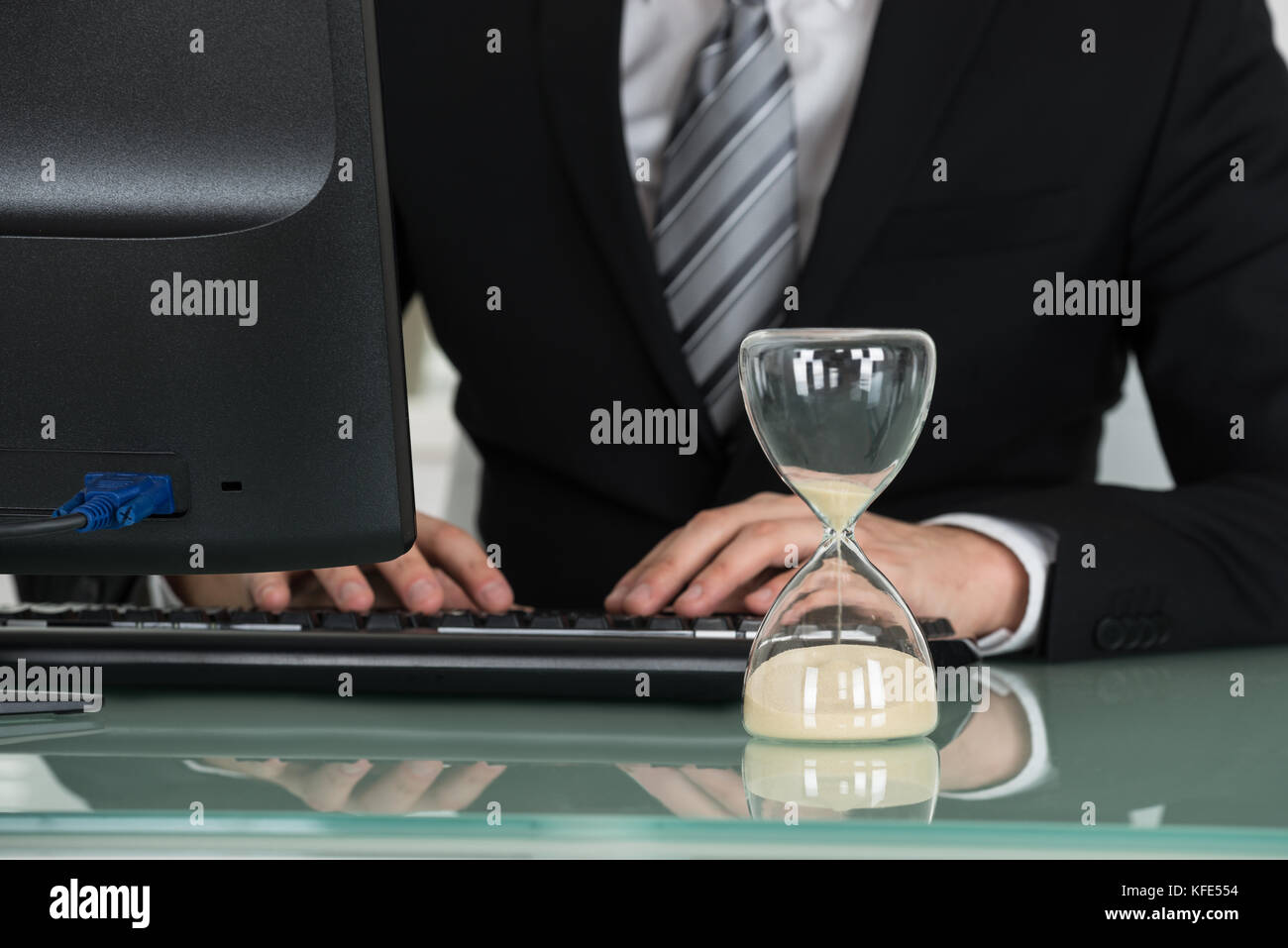 Businessman Working On Computer With Hourglass On Desk Stock Photo - Alamy