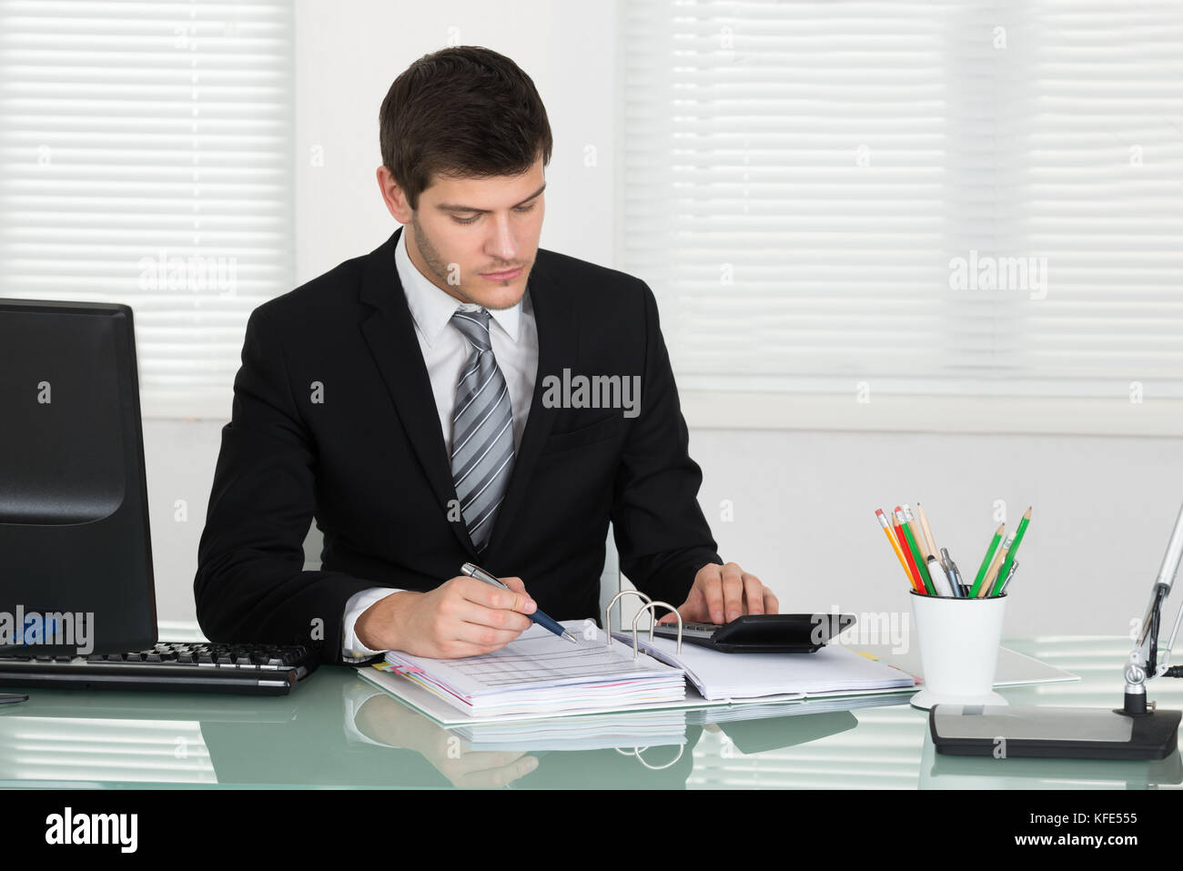 Photo Of Young Businessman Calculating Bill In Office Stock Photo - Alamy