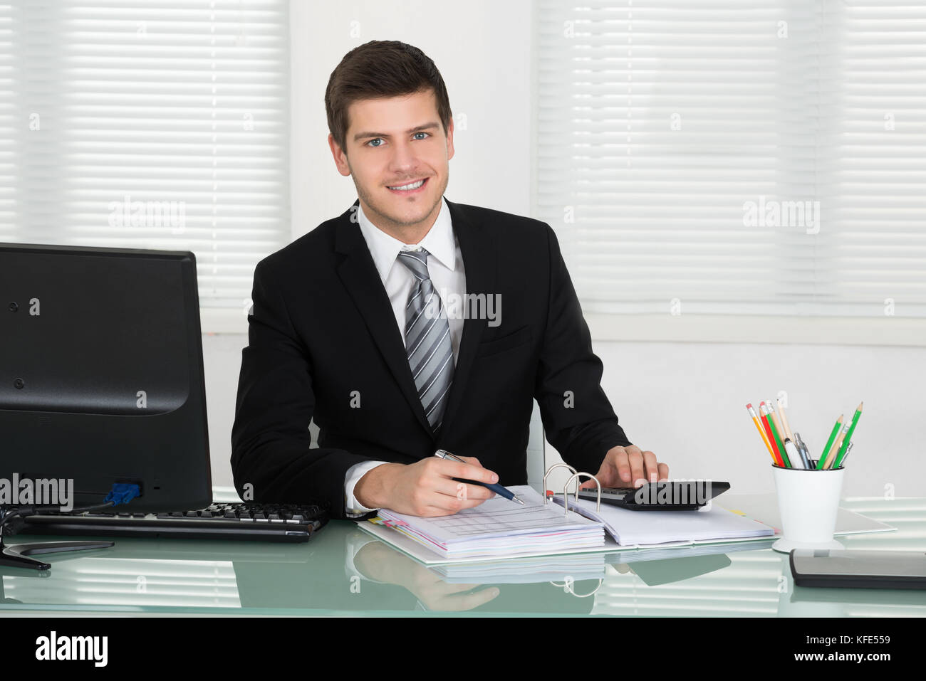 Happy Young Businessman Calculating Bill In Office Stock Photo - Alamy