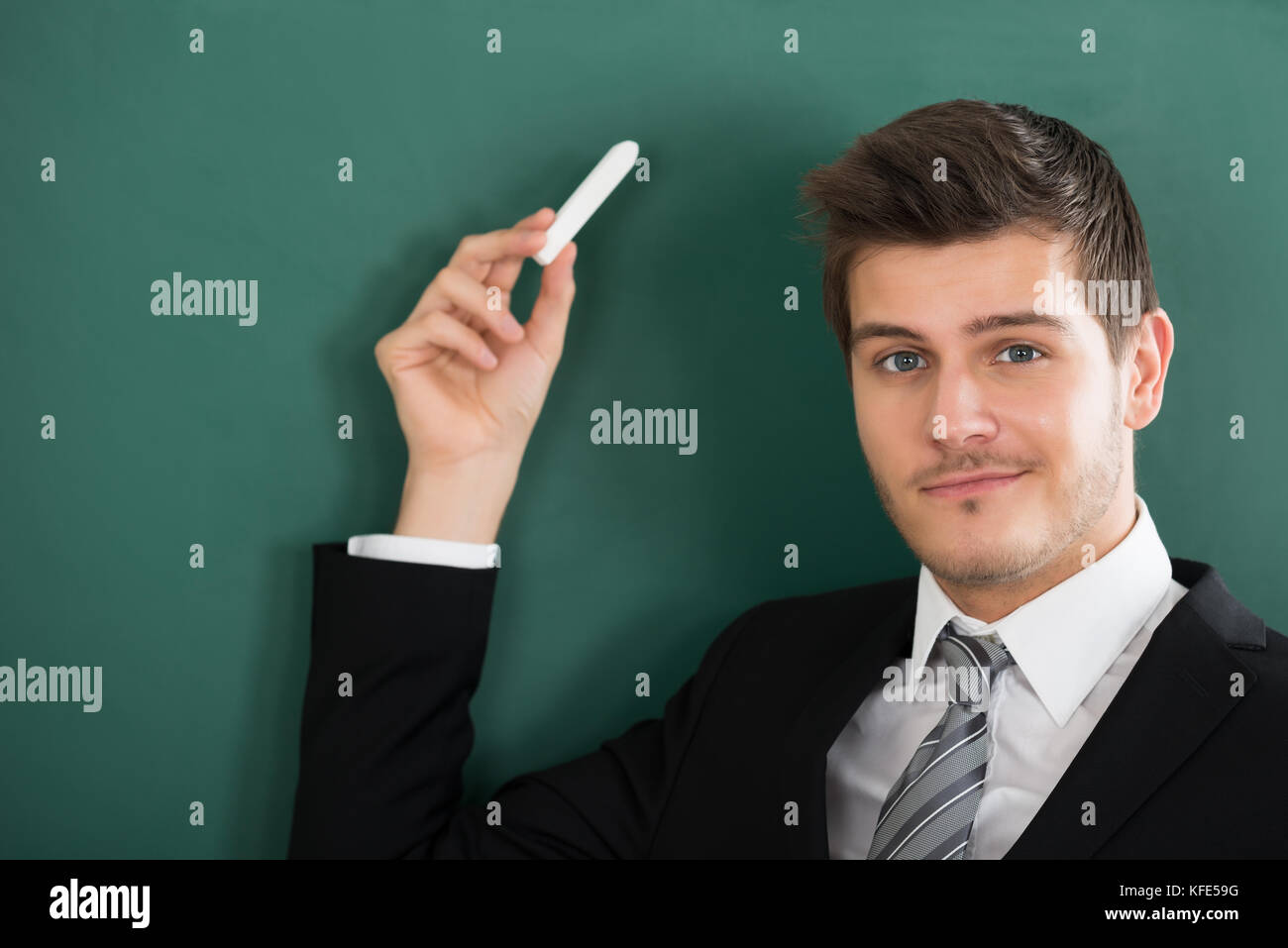 Young Businessman Holding Chalk In Front Of Blackboard Stock Photo - Alamy