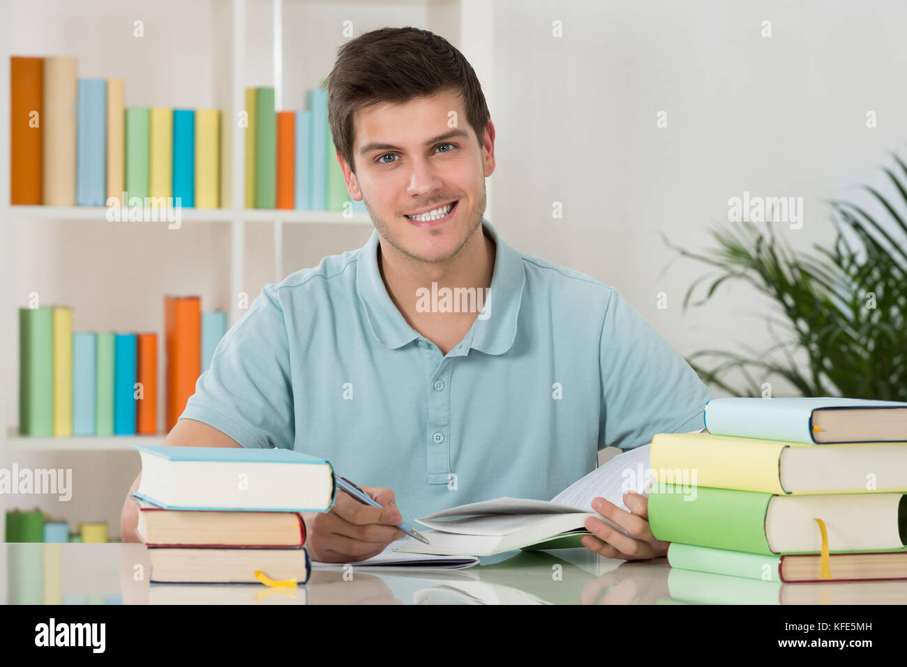 Photo Of Young Man Reading Book In Library Stock Photo - Alamy