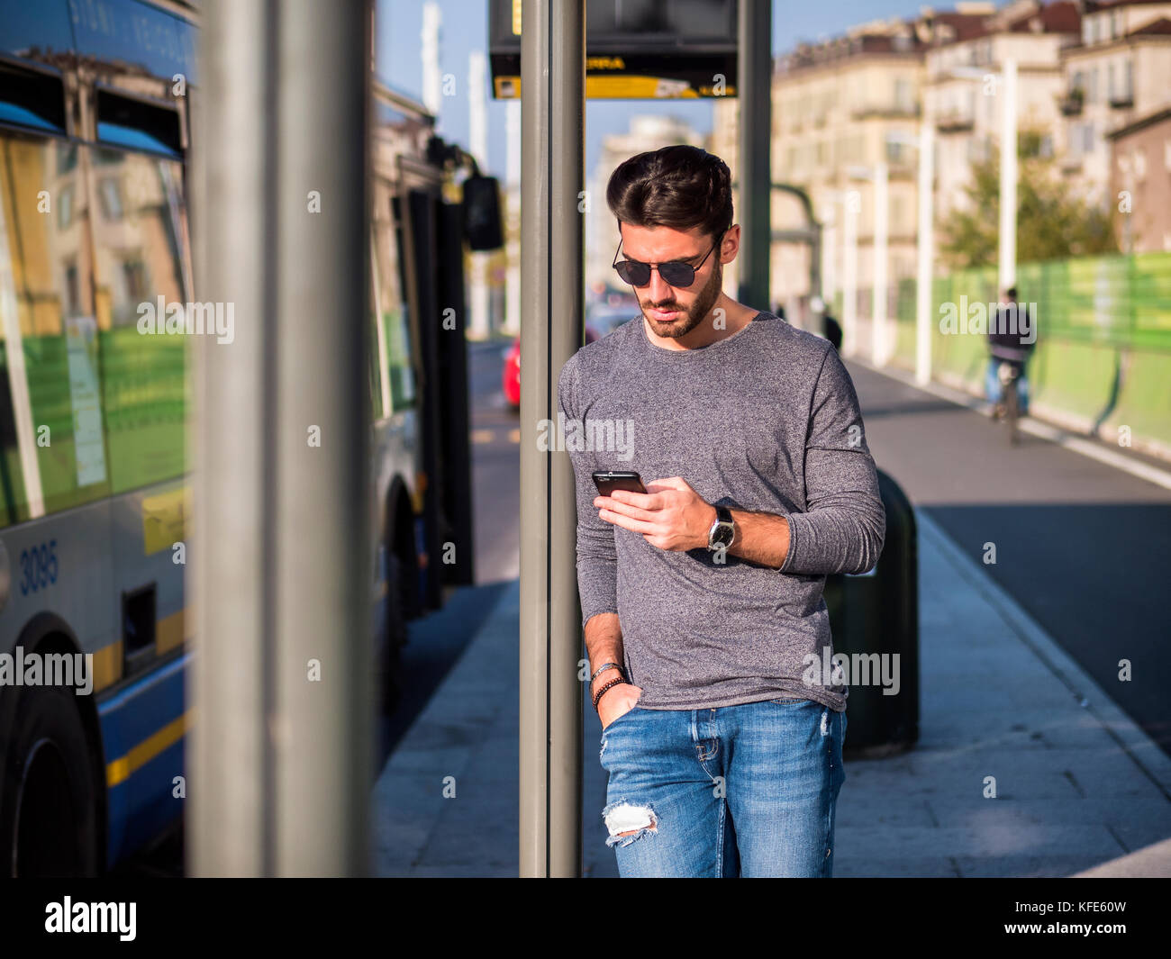 Man using phone at bus stop Stock Photo - Alamy