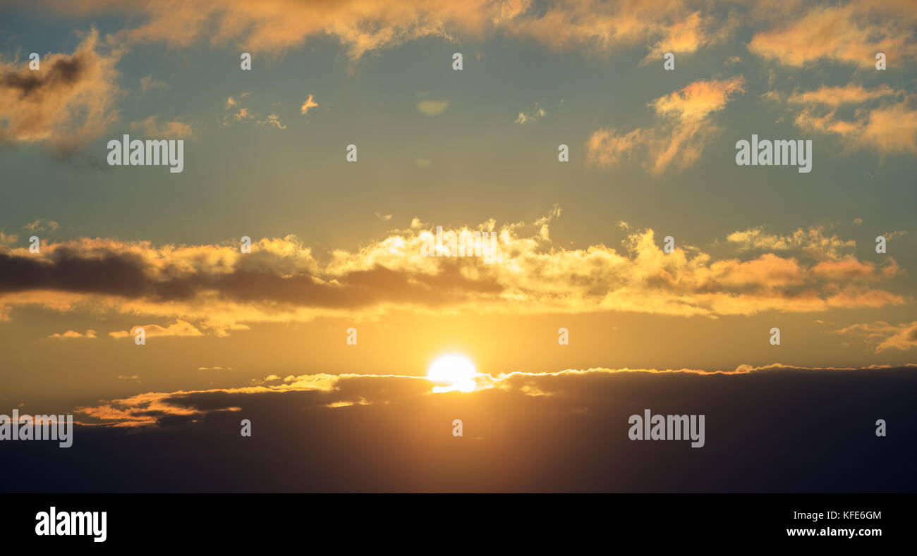 Beautiful sunset on colorful sky. Gold sun lightens the clouds. The sun ...