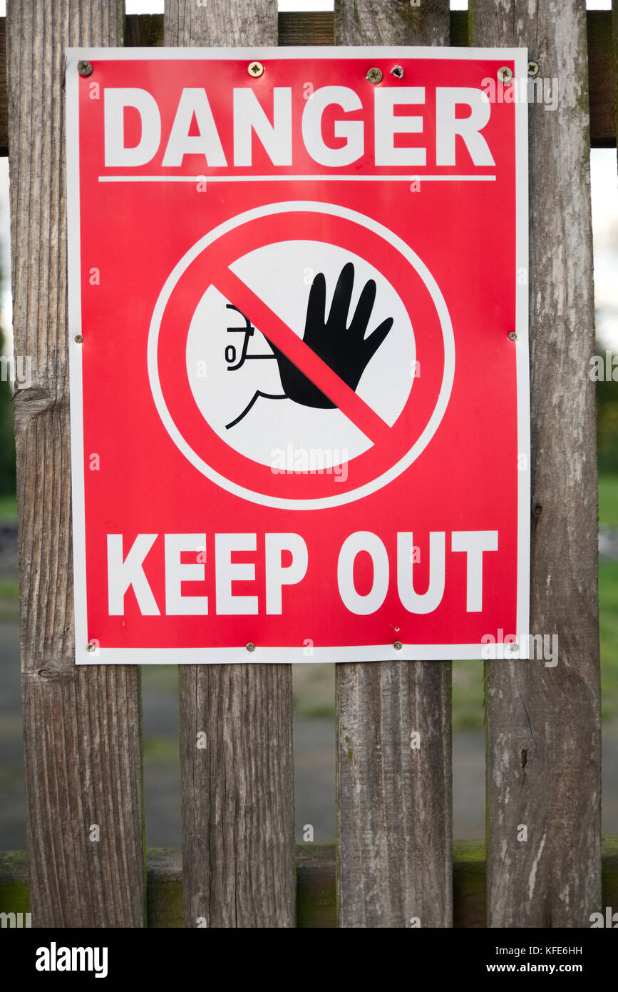 Red, white and black Danger keep out sign screwed on wooden fence Stock ...