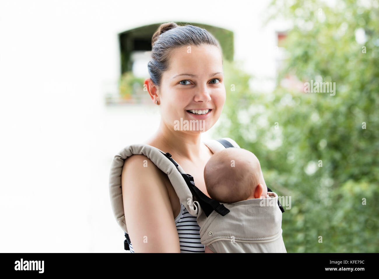 Portrait Of A Smiling Mother Carrying Her Baby In A Baby Carrier Stock ... Portrait Of A Smiling Mother Carrying Her Baby In A Baby Carrier Stock ...