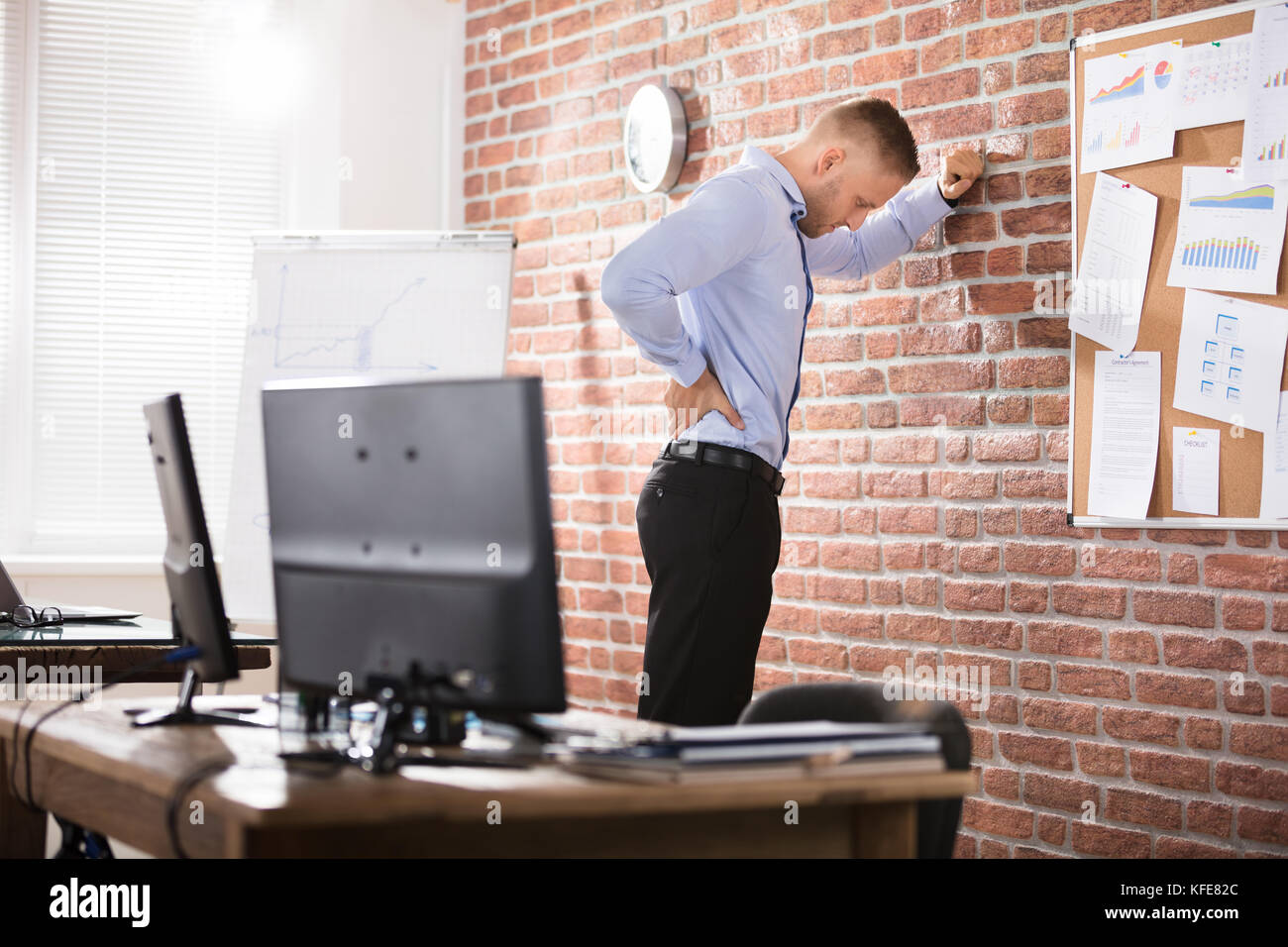 Businessman Leaning Against The Brick Wall Having Back Pain In Office ...