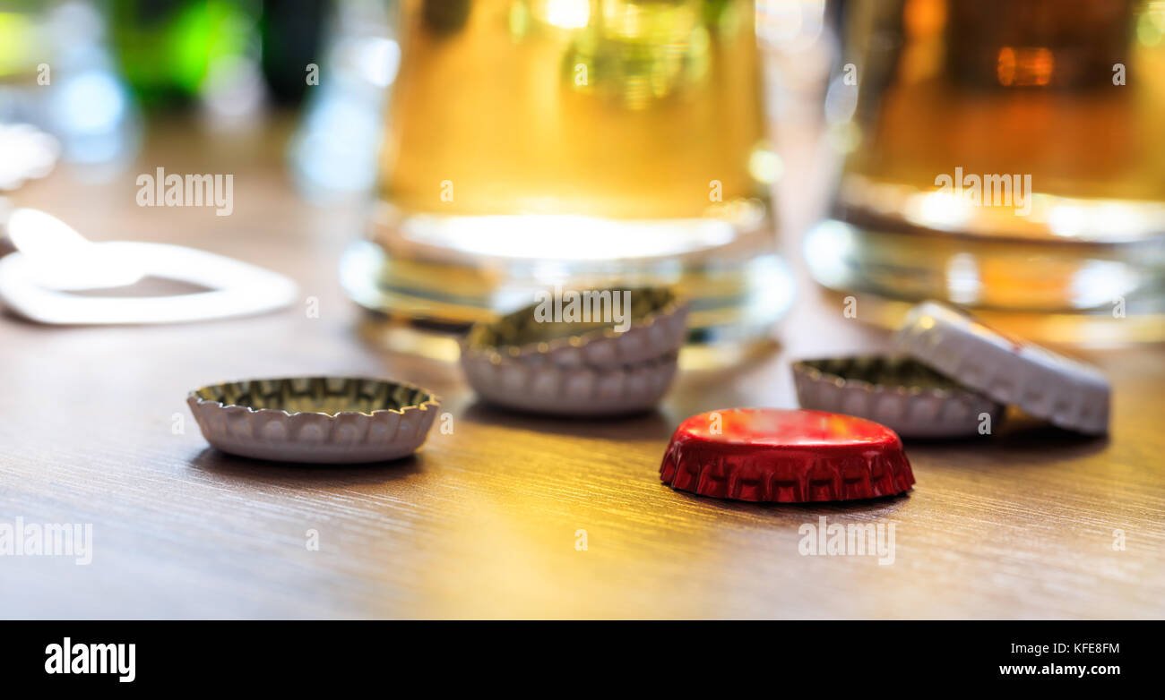 Beer caps and glasses of beer on a pub background. Closeup on the beer ...