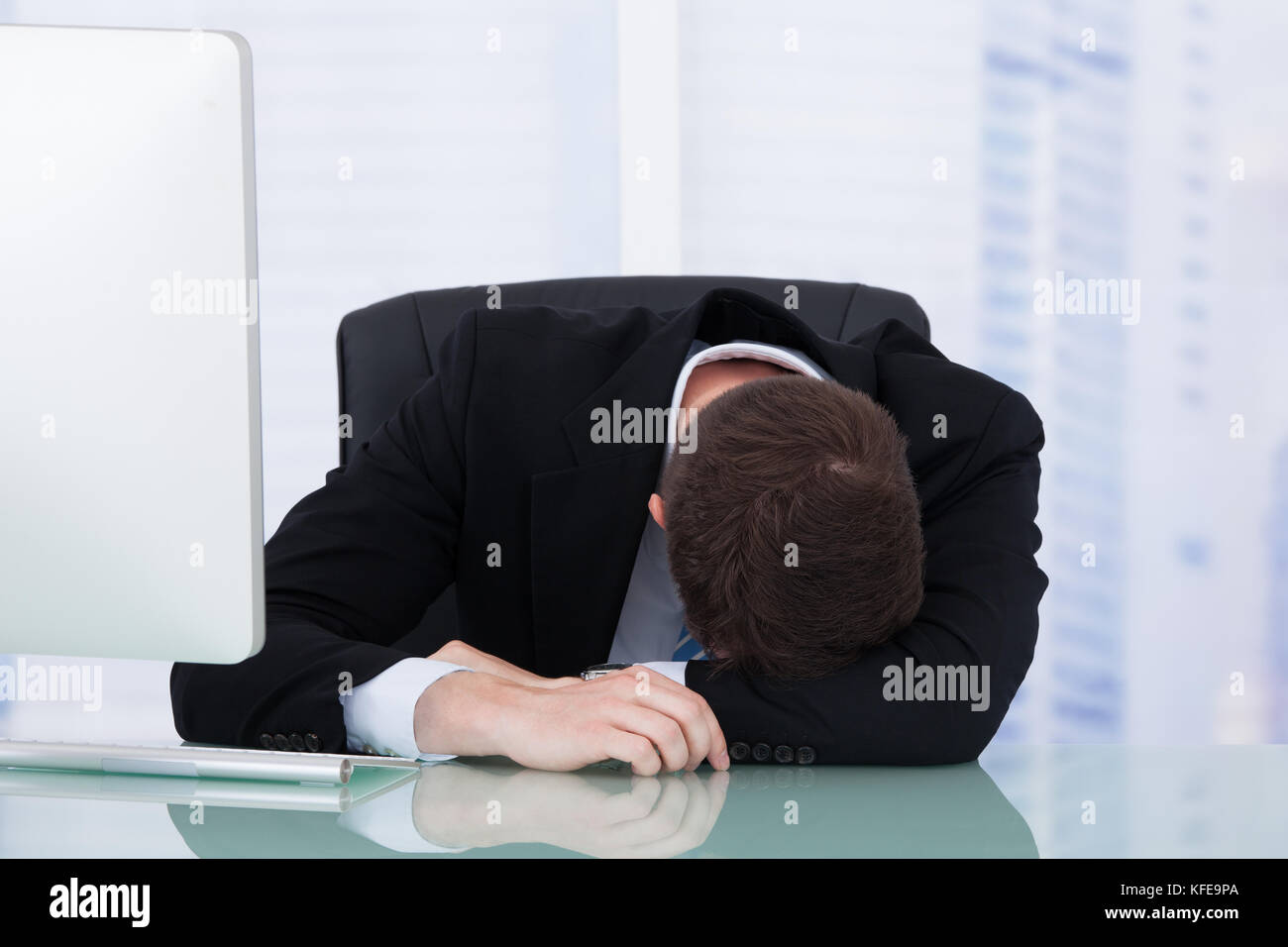 Tired young businessman resting at office desk Stock Photo - Alamy