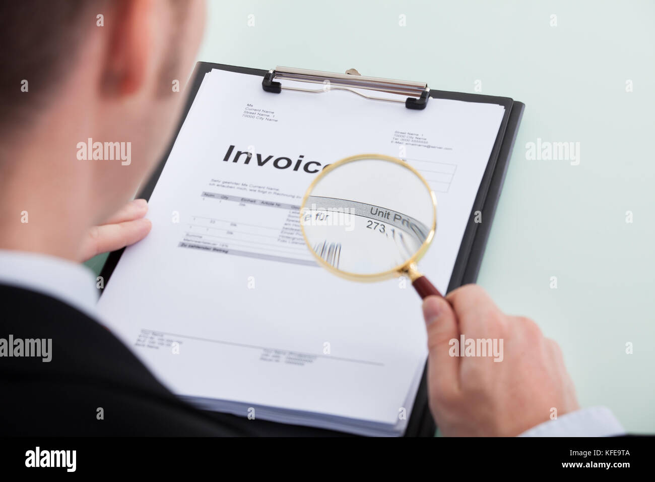 Cropped image of young businessman examining invoice through magnifying ...