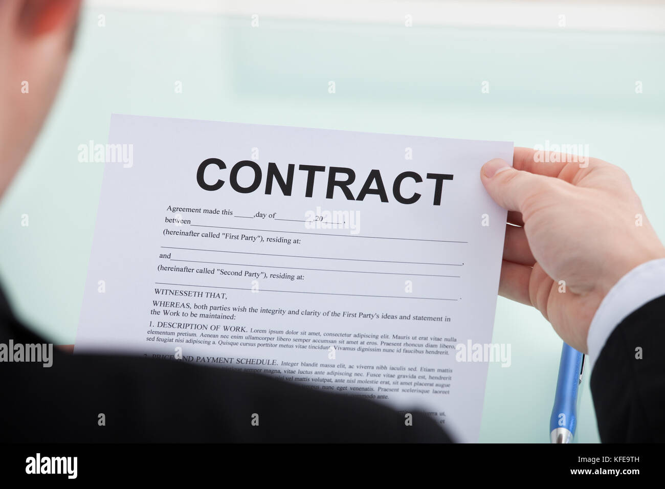 Cropped image of young businessman reading contract paper at office ...