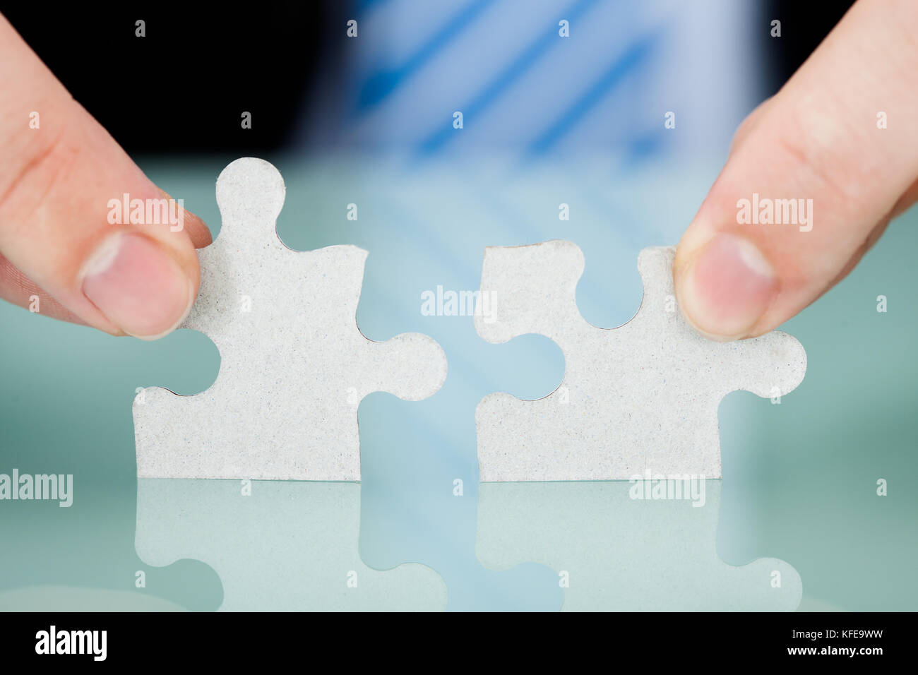 Closeup of young businessman joining puzzle pieces at office desk Stock ...