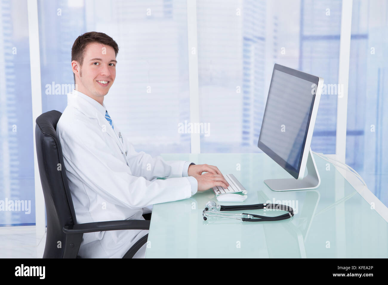 Portrait of young male doctor using computer at desk in clinic Stock ...