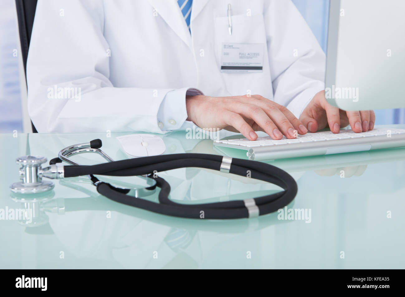 Midsection of young male doctor using computer at desk in clinic Stock ...