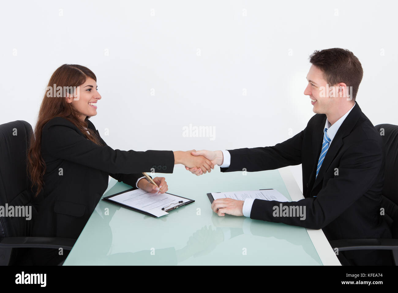 Young businesswoman shaking hand of male candidate during job interview ...