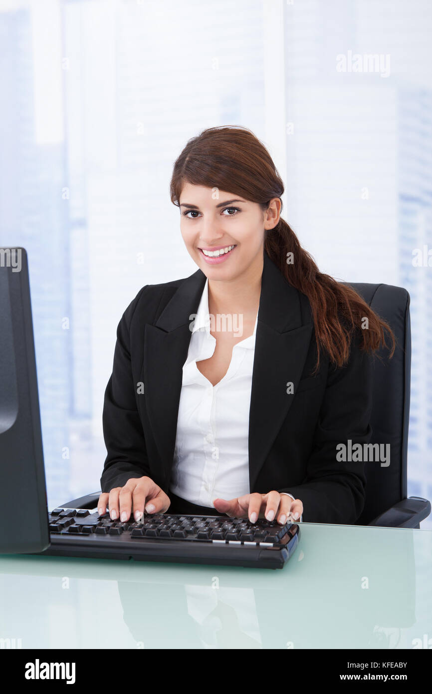 Young businesswoman using computer at office desk Stock Photo - Alamy