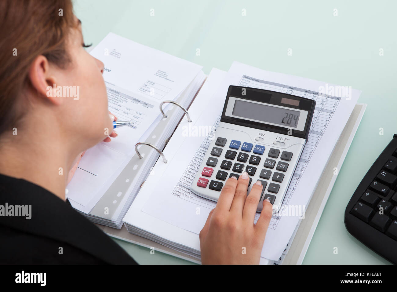 Cropped image of young businesswoman calculating bills at desk in ...