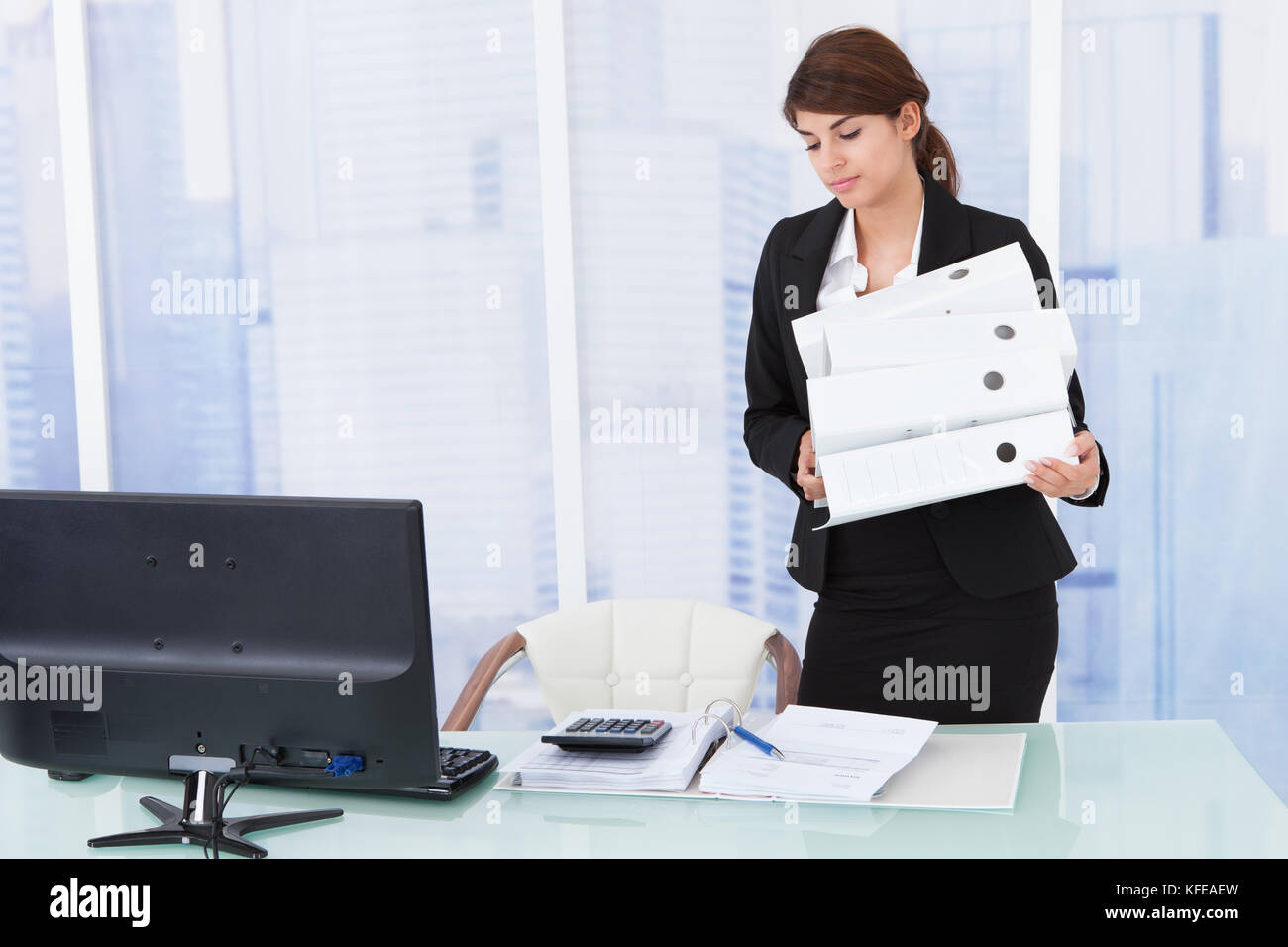 Young businesswoman carrying stacked binders at office desk Stock Photo ...