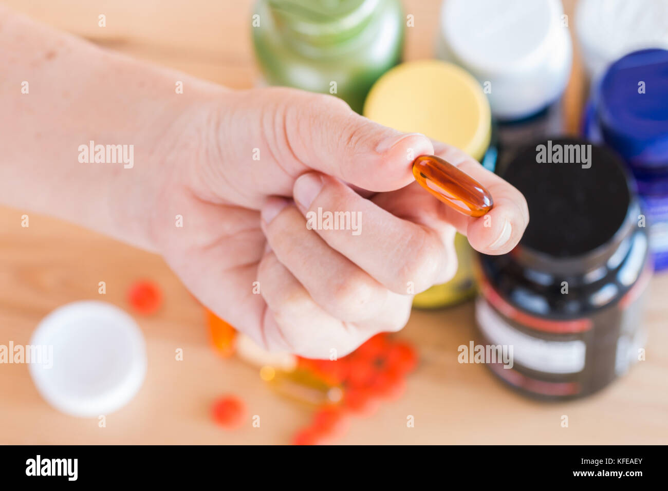 Close up of hand is holding a vitamin supplement on medicine bottles ...