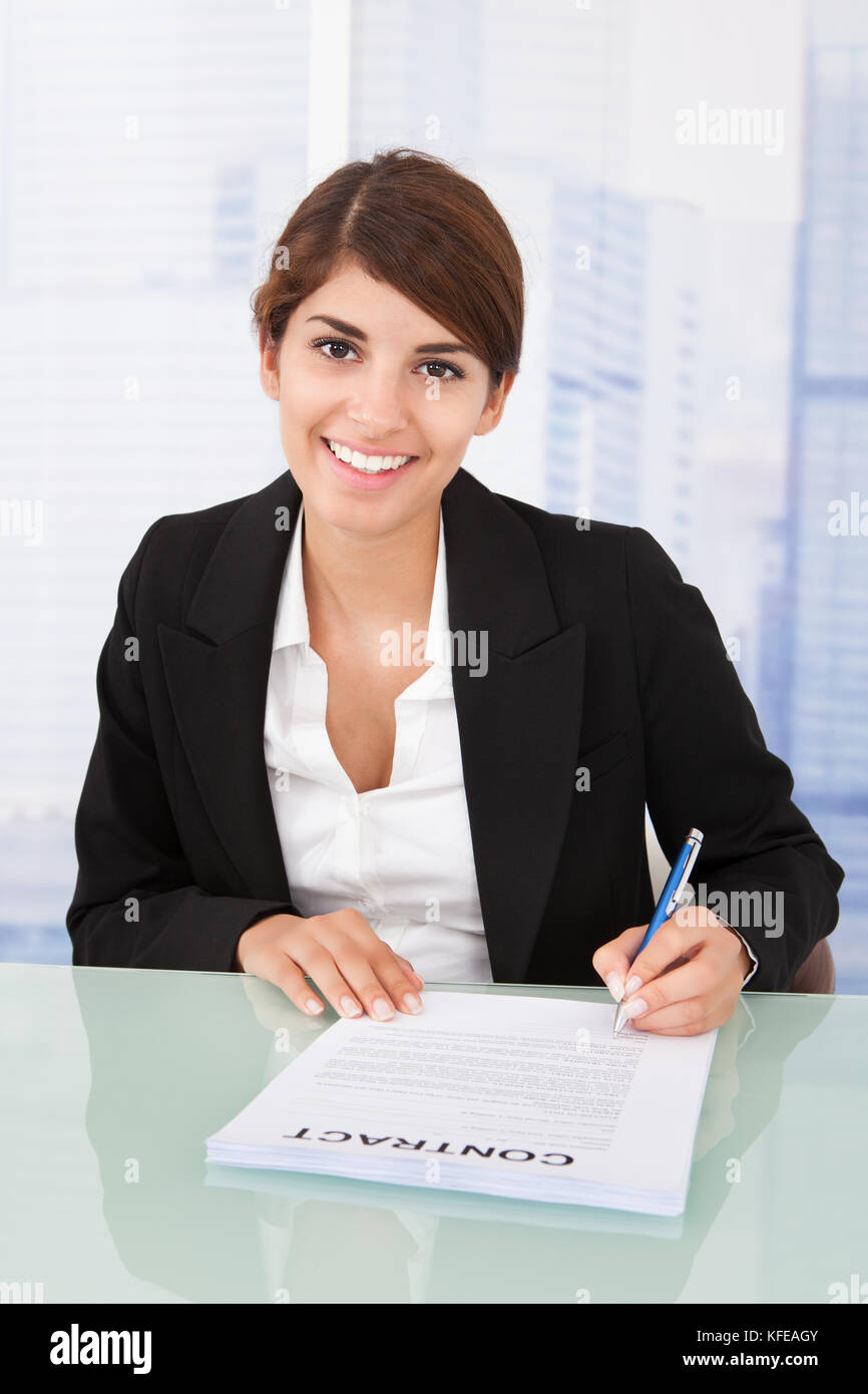 Professional woman signing document at desk hi-res stock photography ...
