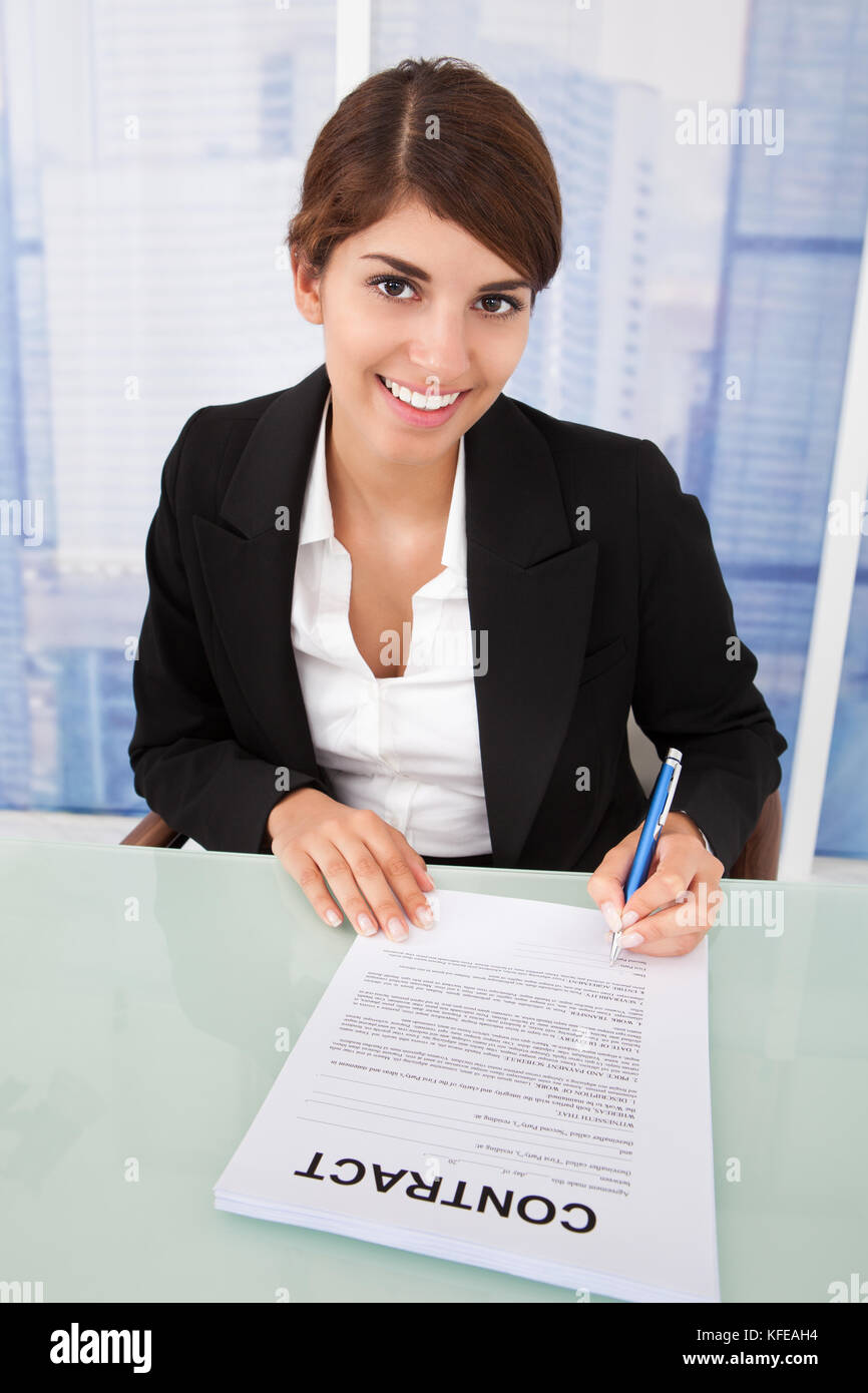 Professional woman signing document at desk hi-res stock photography ...