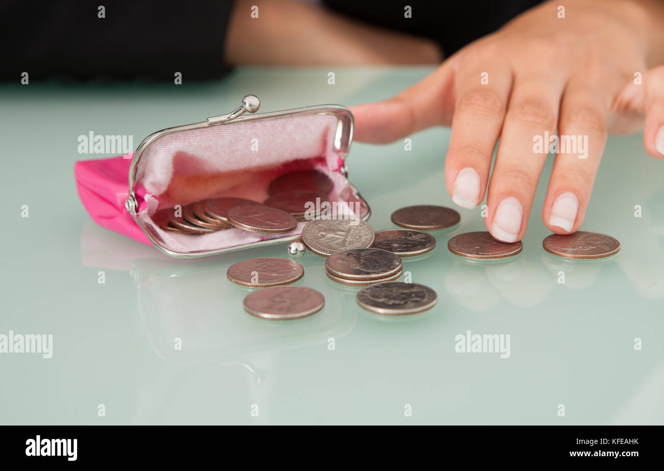 Midsection of businesswoman counting coins spilled from pink purse at ...