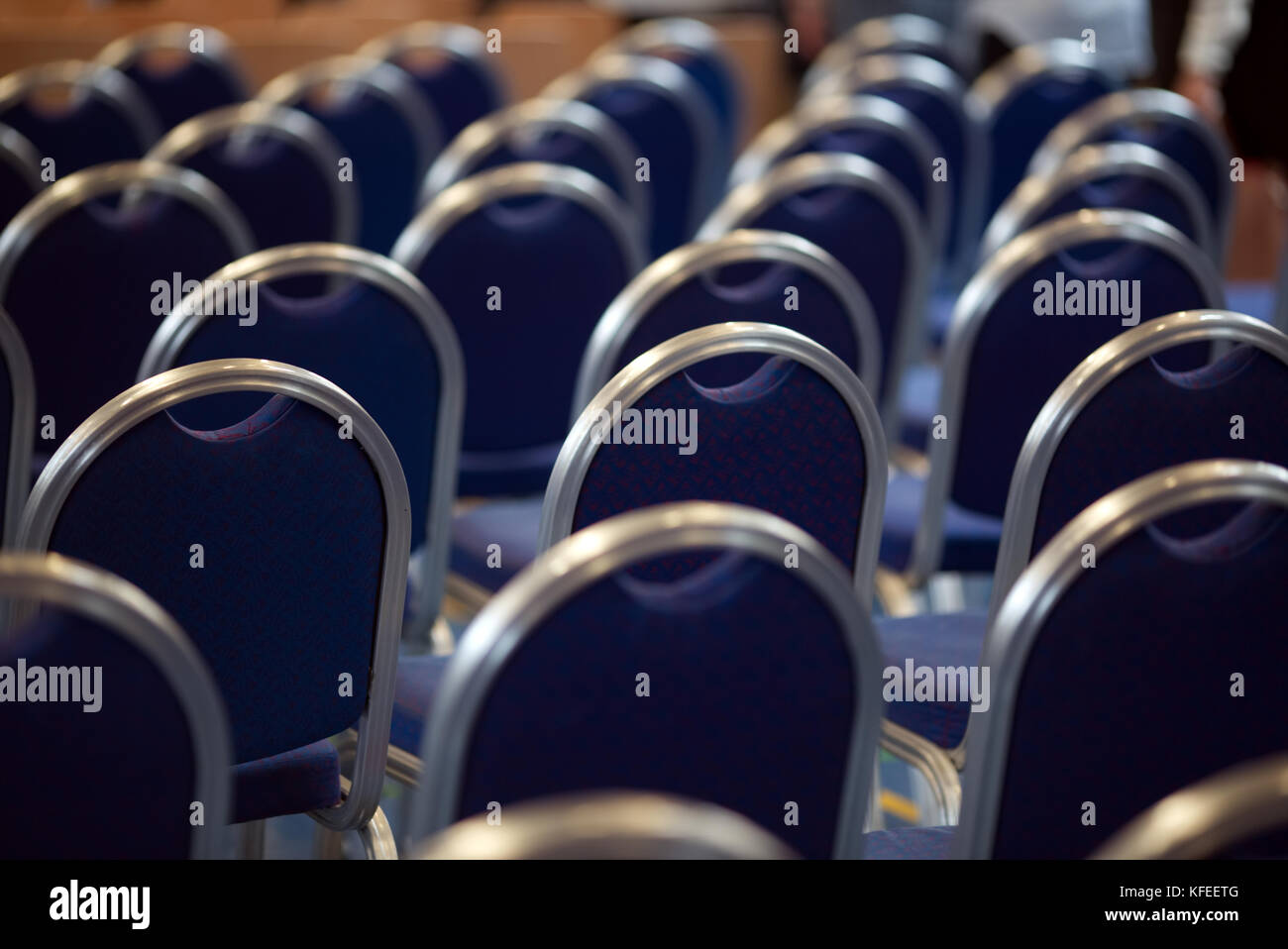 Rows of empty metal chairs in a large assembly hall.Empty chairs in ...