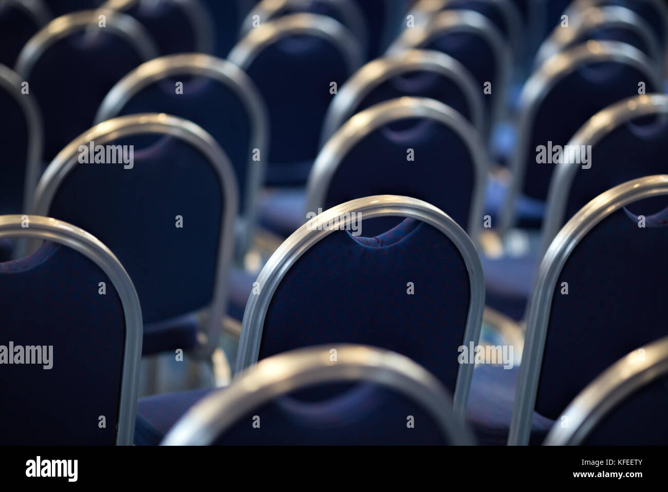 Rows of empty metal chairs in a large assembly hall.Empty chairs in ...