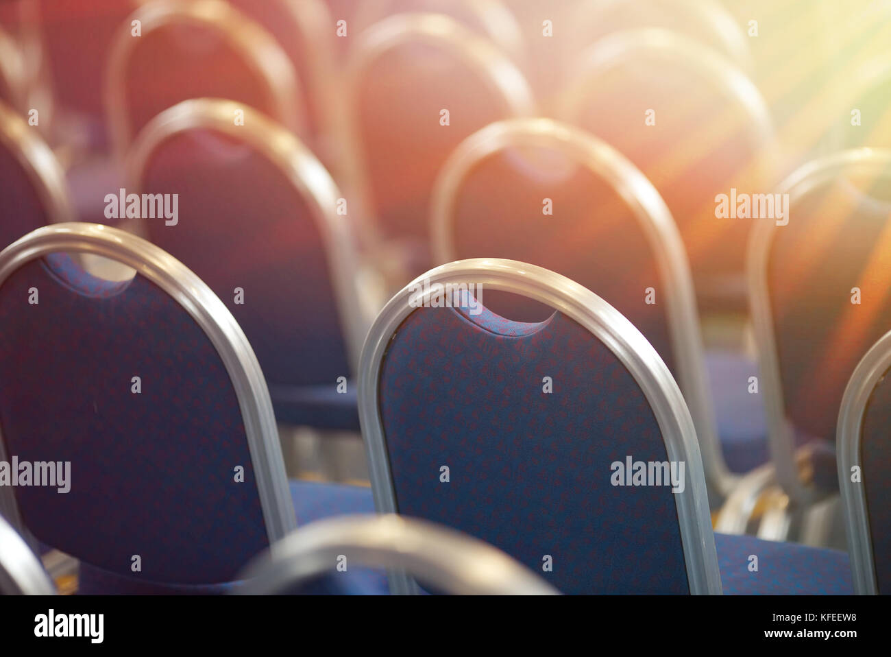 Rows of empty metal chairs in a large assembly hall.Empty chairs in ...