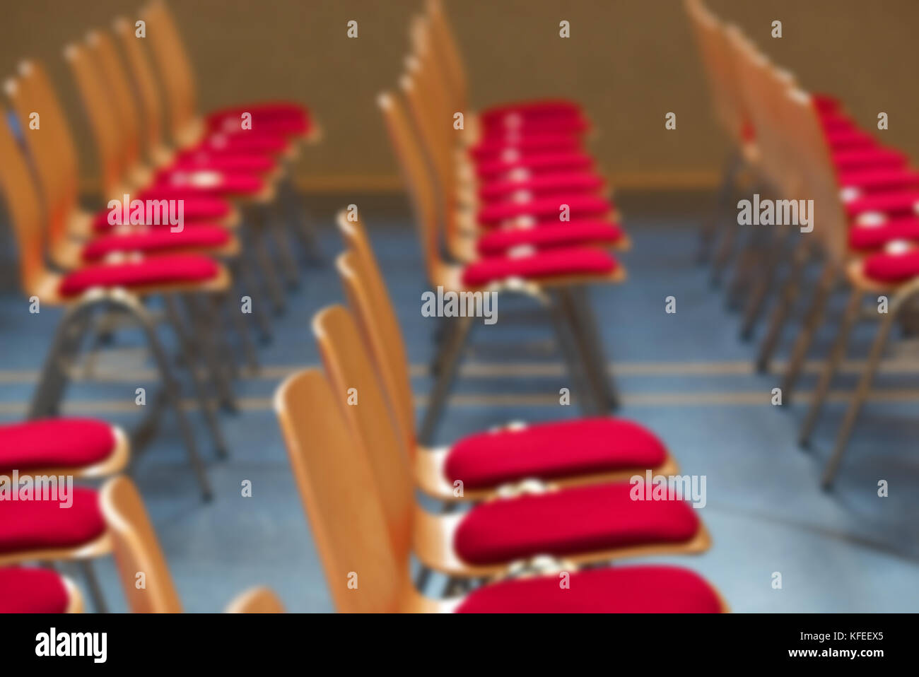 Blurred rows of empty wooden chairs in a large assembly hall.Empty ...