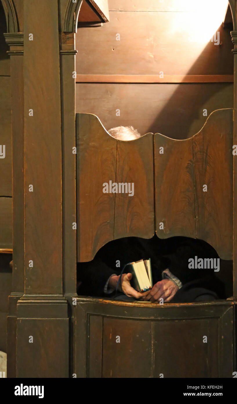 old priest inside the confessional in a Christian church waiting for ...