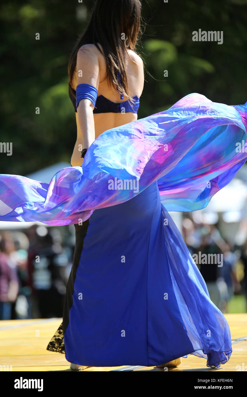 young woman with long black hair and blue skirt fluttering during a ...