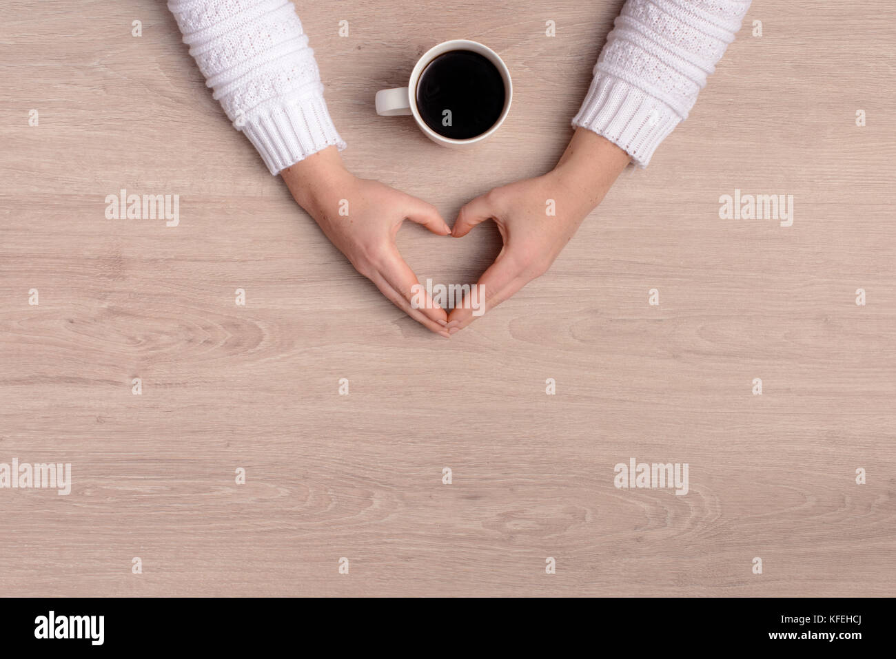 Young woman sittin at table making heart shape with her palms Stock ...