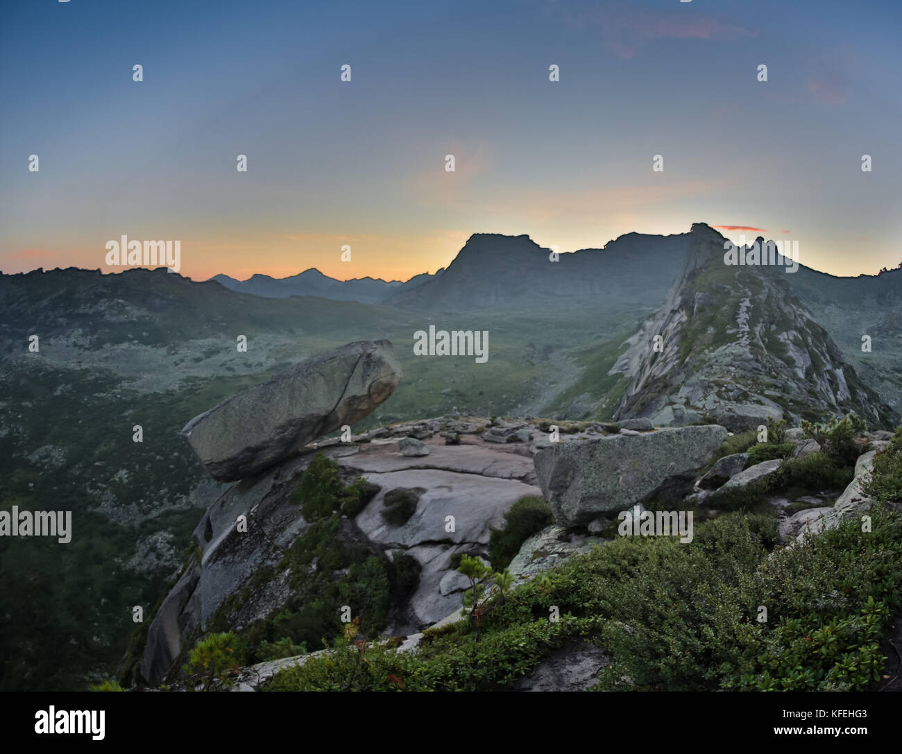 Hanging stone lies on sloping surface of mountain above precipice. A ...