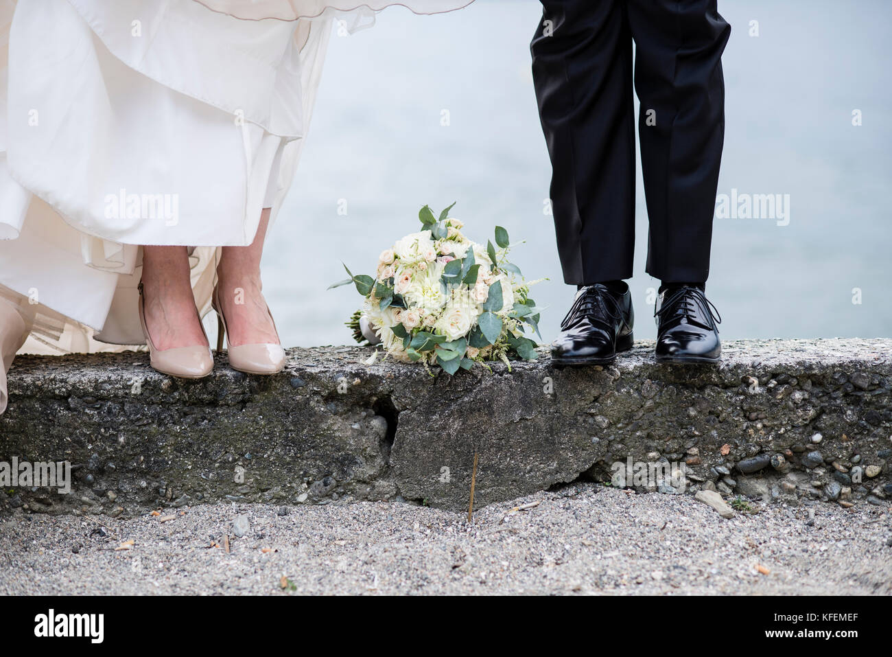 bride and groom feet on a low wall with bouquets in the center Stock ...