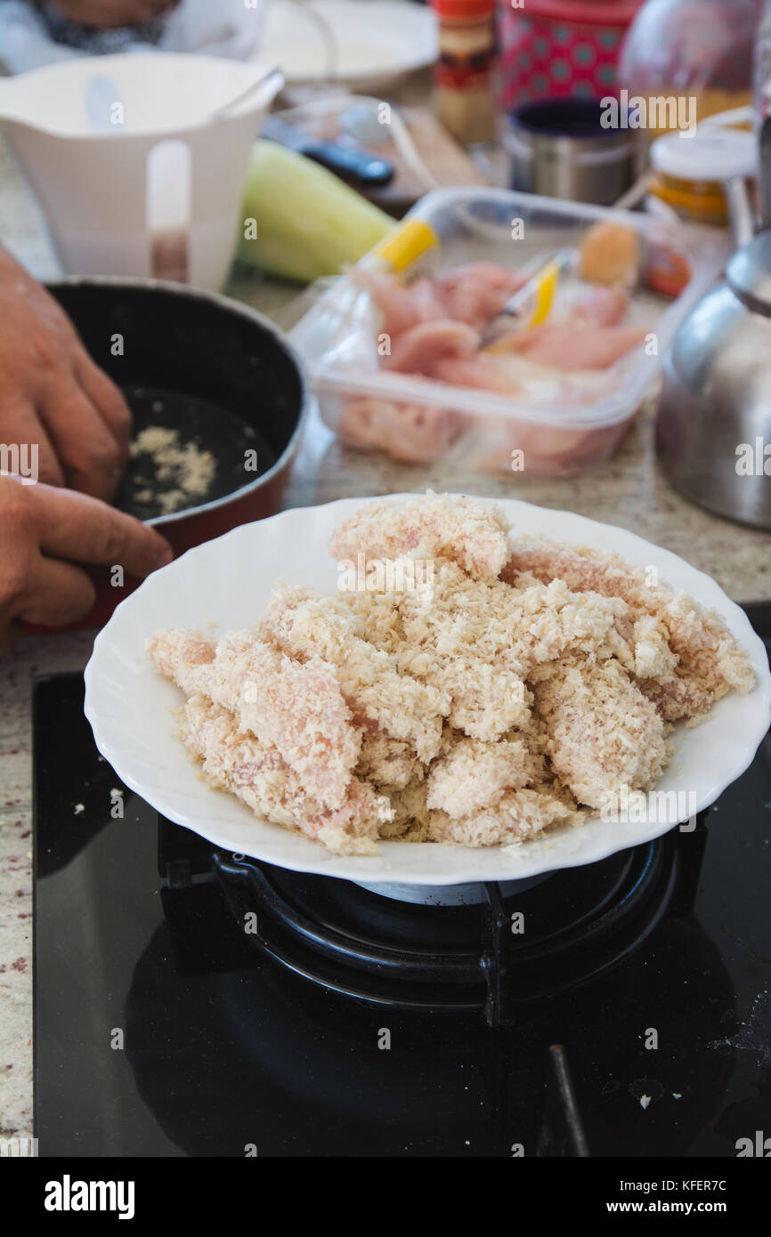 Person breading with breadcrumbs and corn, the steaks of chicken to fry ...