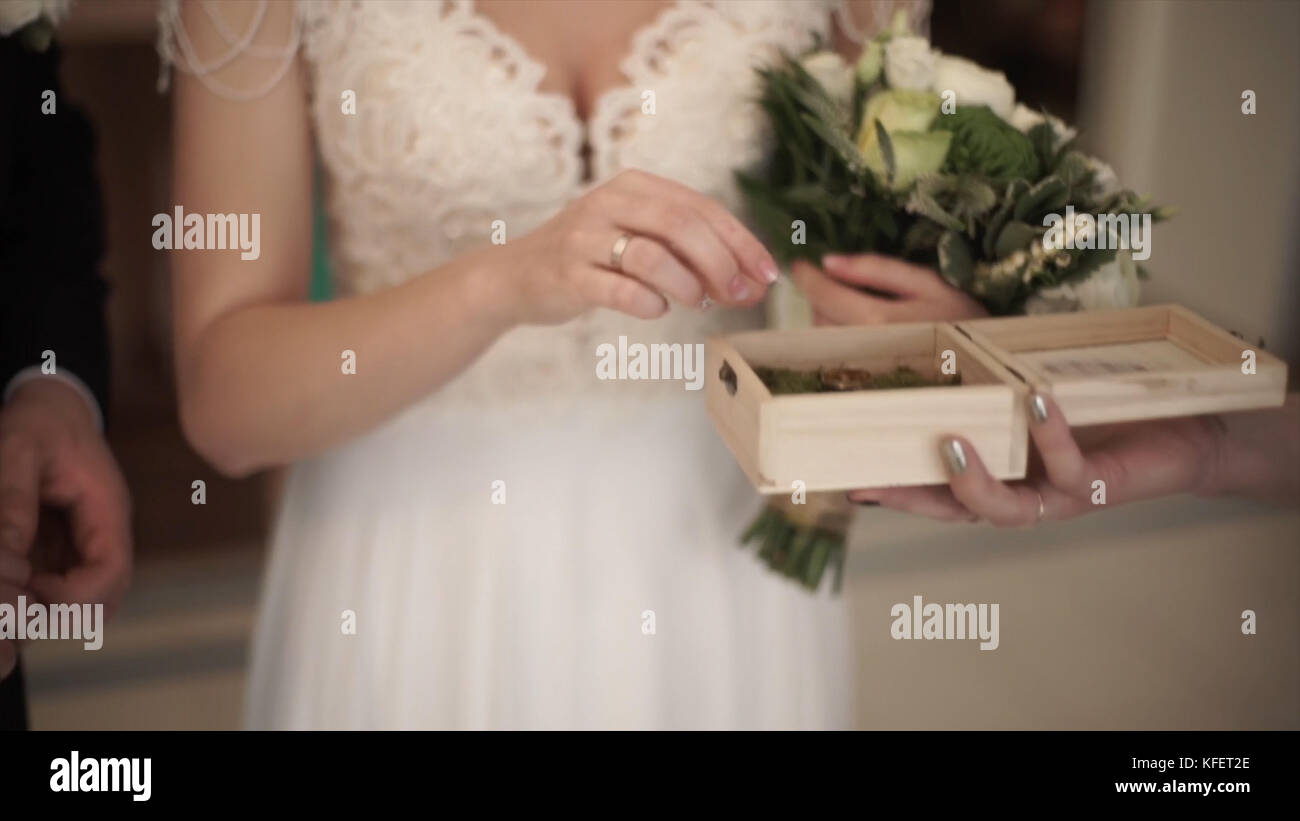 Closeup of a bride putting a gold wedding ring onto the groom's finger ...